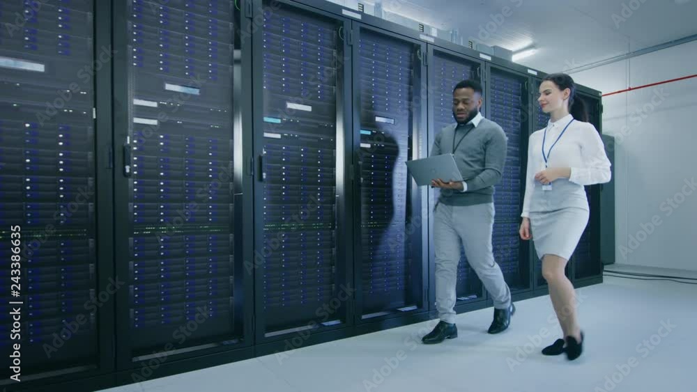 Black IT Technician with a Laptop Computer Gives a Tour to a Young ...