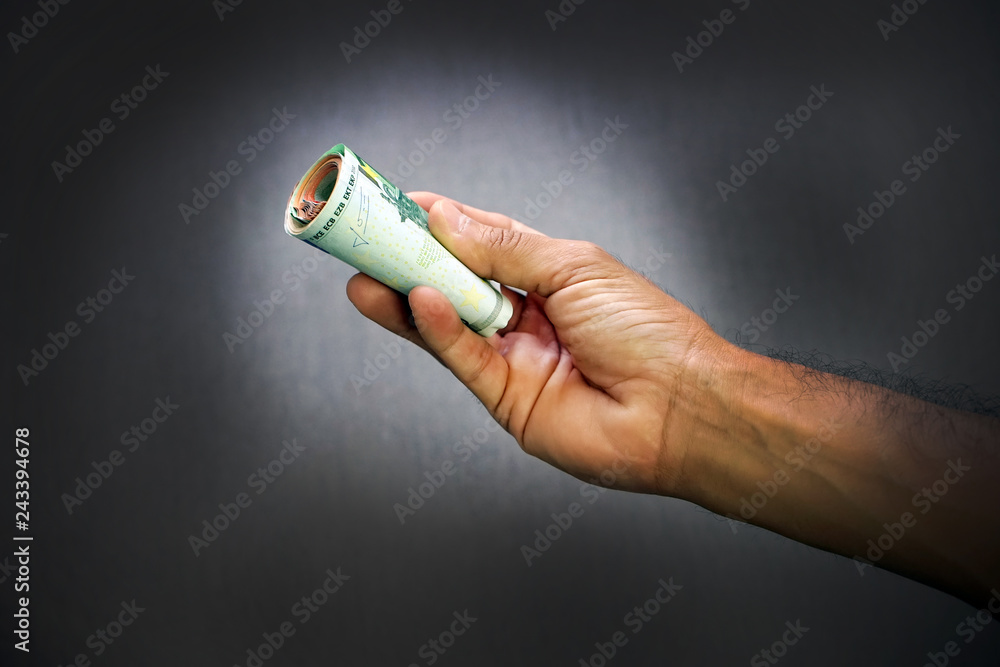 Hand of office worker gives a bribe roll euro banknote to an employee ...
