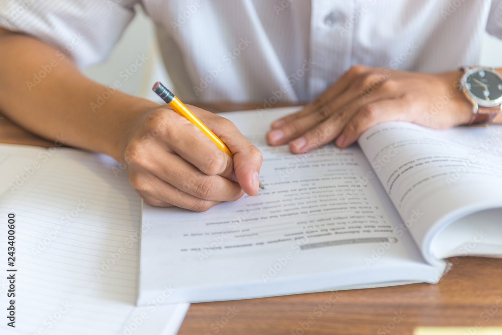 Student using pencil to take note and highlight main ideas on workbook ...