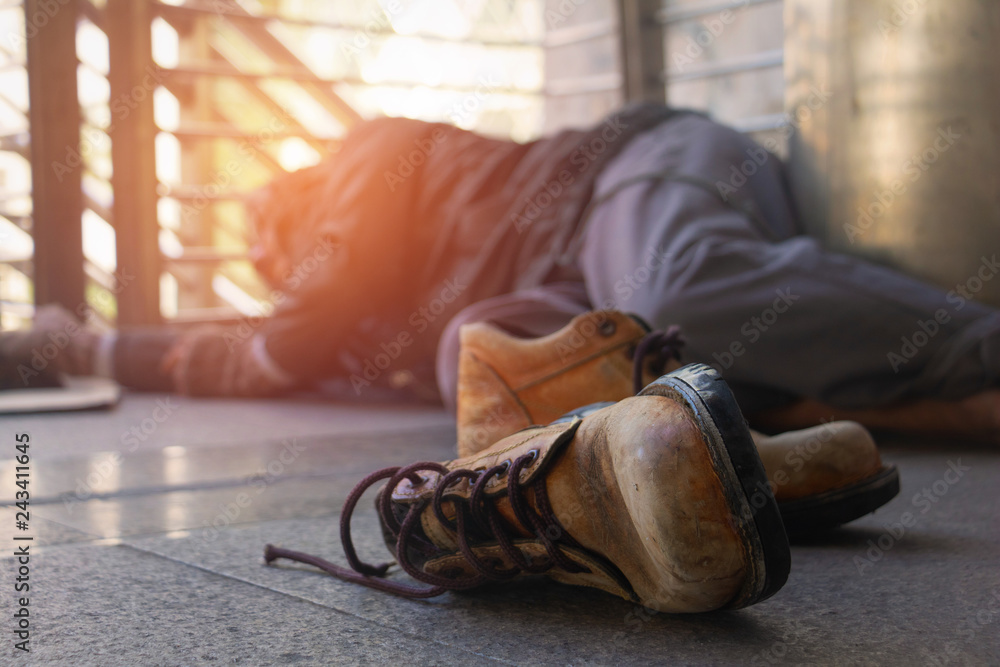 Foto de Old shoes and homeless. Homeless man is lie down on walkway in ...