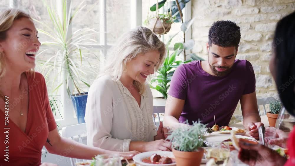 Multi-ethnic group of young adult friends eating lunch together at a ...