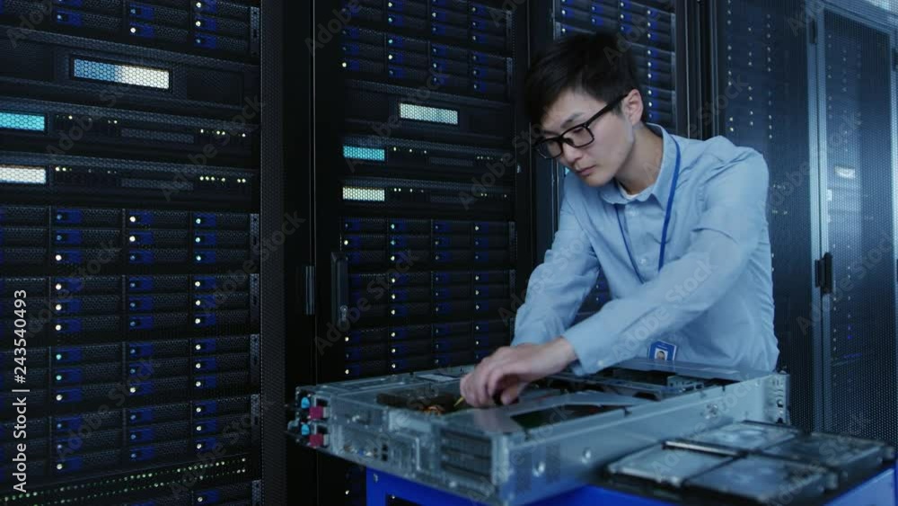 In the Modern Data Center: IT Technician Working with Server Racks, on ...