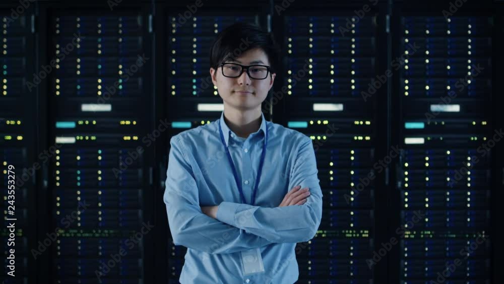 In the Modern Data Center: IT Engineer Wearing Protective Headphones Installs New Hardware for ...