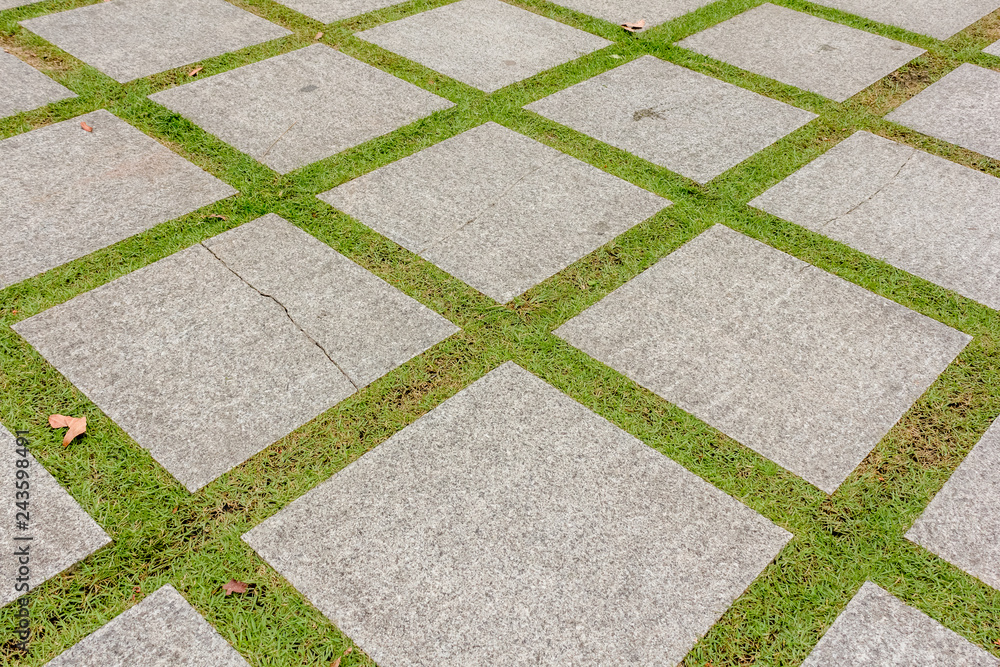 Pattern of square cement floor tiles with green grass field ...