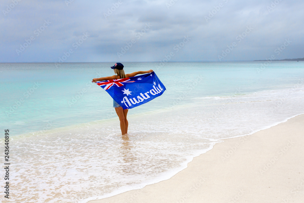 Aussie culture. A woman standis on a stunning beach holding proudly the ...