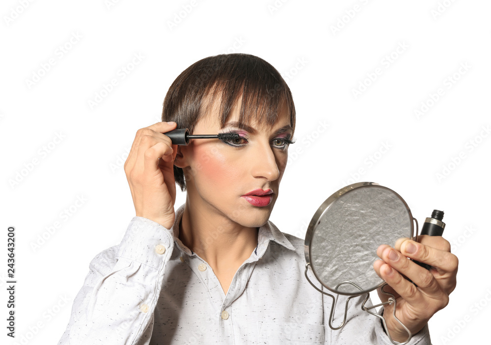Portrait of transgender man applying makeup onto his face against white ...