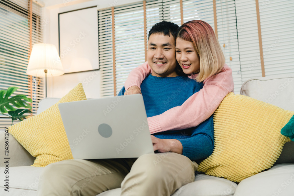 Attractive Asian sweet couple using computer or laptop while lying on ...