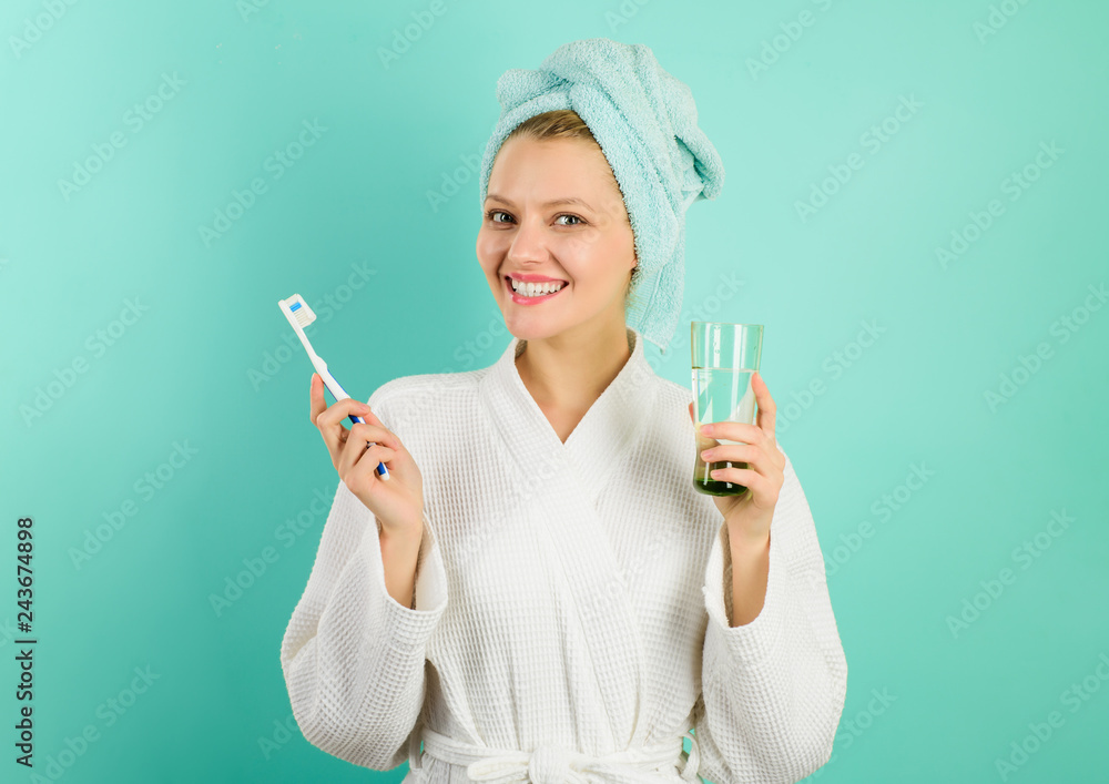Morning routine. Woman with towel on head cleaning teeth with ...