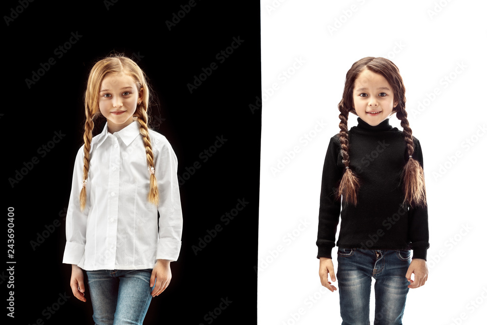 The portrait of two happy girls on a white and black studio background ...