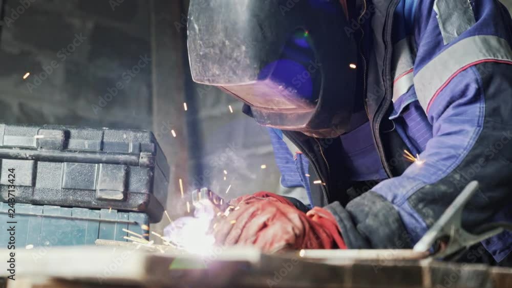 Side view welder in welding mask welds two metal parts. Workman in ...