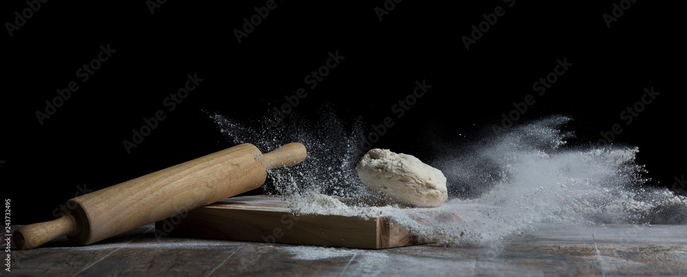 Studio photo of a ball of bread dough falling on flour with roller ...