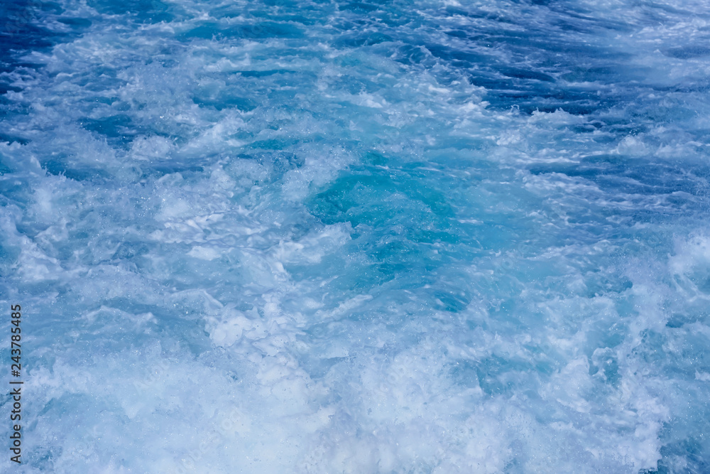Boiling water in the ship's trail as background. Blue ocean wave ...