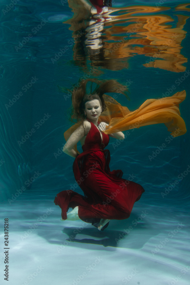 beautiful free diver woman swimming in long red evening dress under ...
