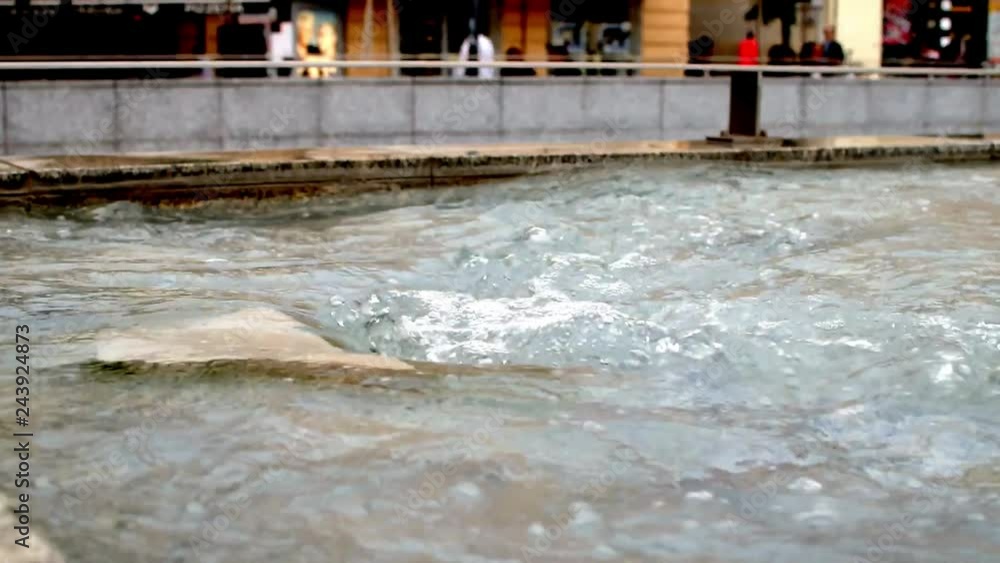 the moving water of an urban modern fountain is seen pouring out of an ...