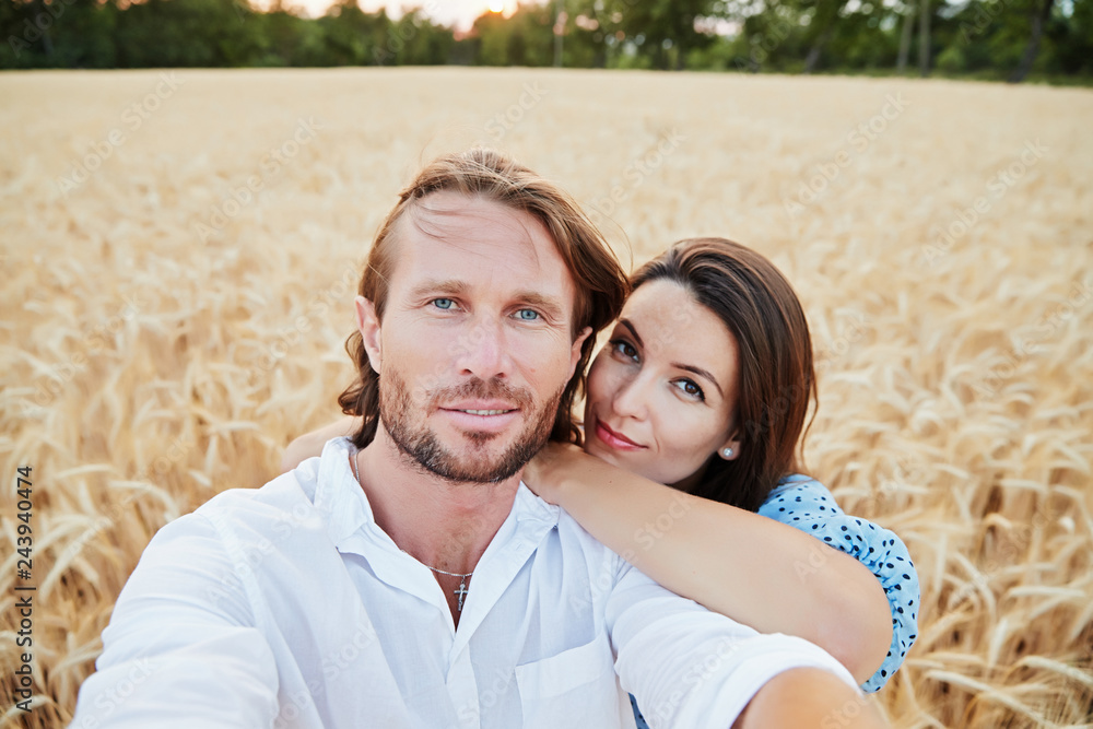 The beautiful couple embraces in the field of a rye and looks in a ...