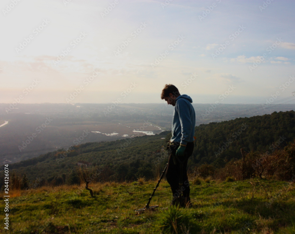 young man in the mountains looks for buried and forgotten treasures ...