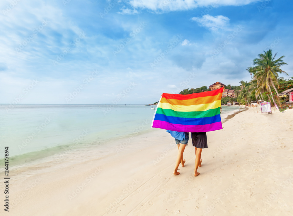 Fotka „Young lesbian couple walks on a bright tropical beach with a ...