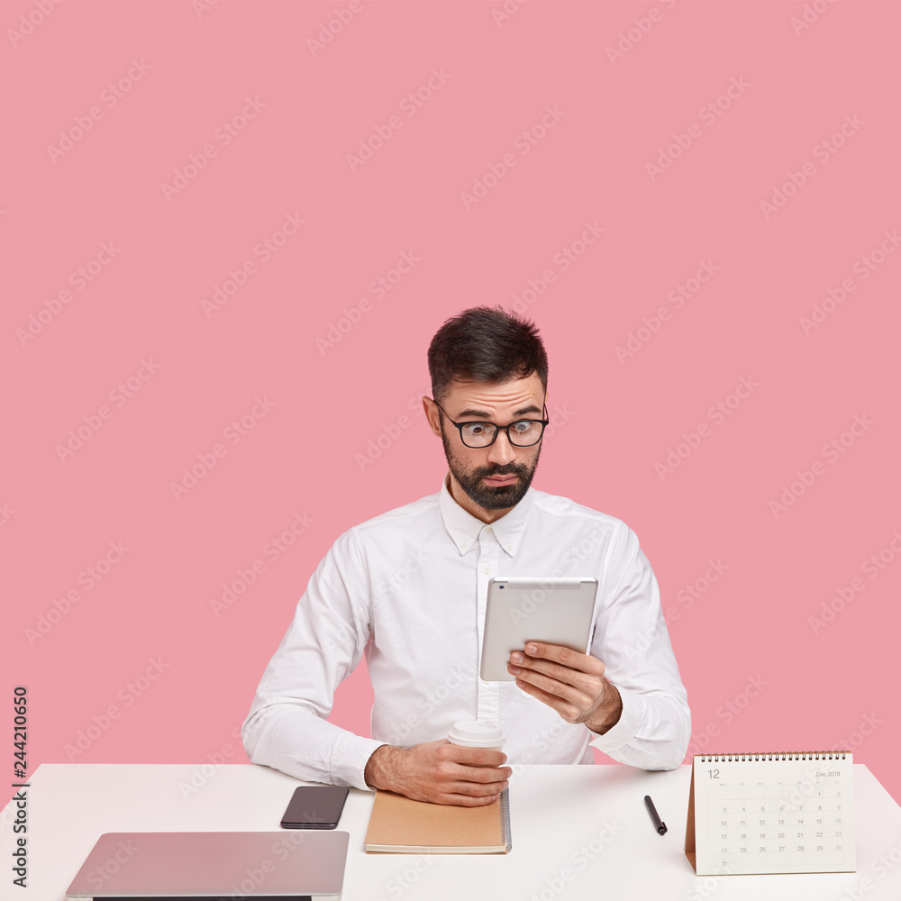 Vertical shot of surprised bearded young man stares at screen of ...
