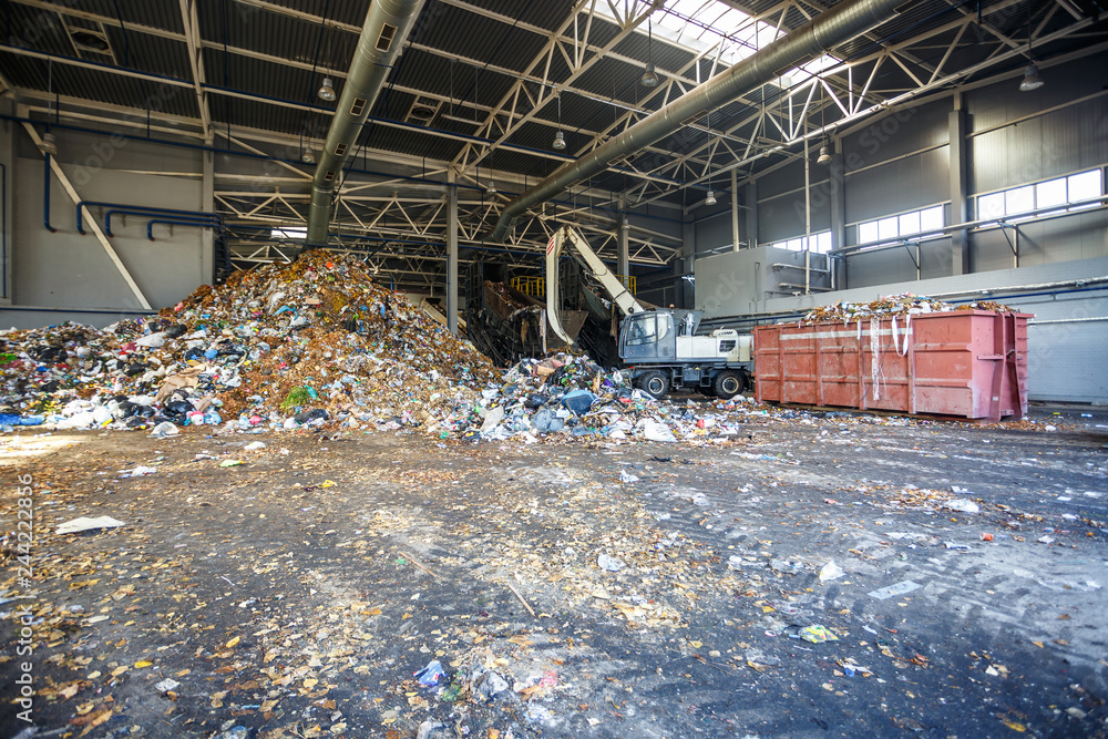Excavator on primary sorting of garbage at waste processing plant ...