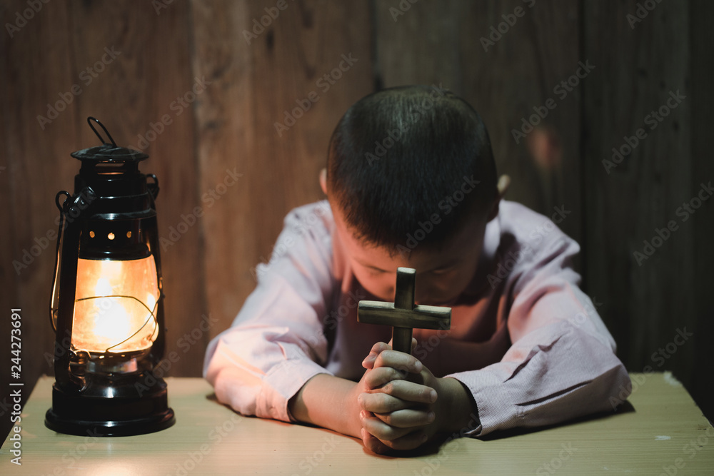 Boy hands holding a holy cross praying to God In the dark and with the ...