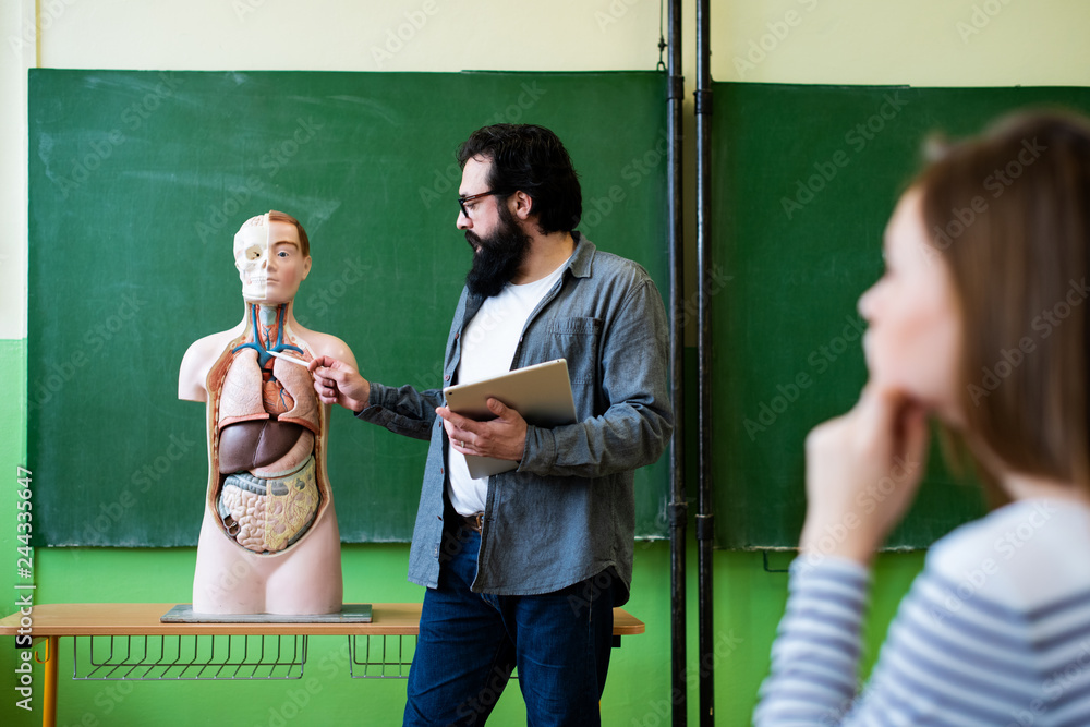 Young male hispanic teacher in biology class, holding digital tablet ...