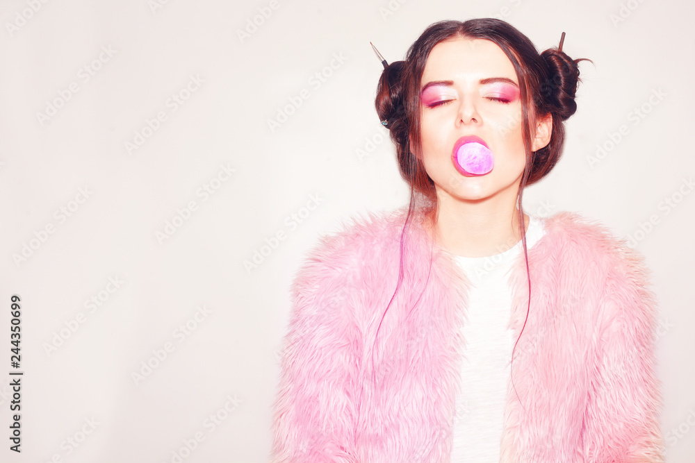 Girl in pink with win buns eats gum. Portrait of a pretty young girl ...