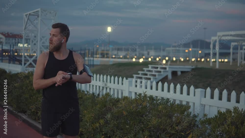 Male runner is training alone in evening time in darkness in city park ...