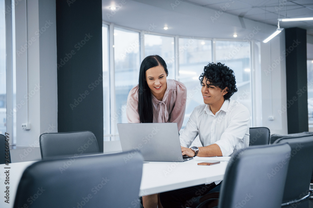 Looking together at computer. Cheerful coworkers in a modern office ...