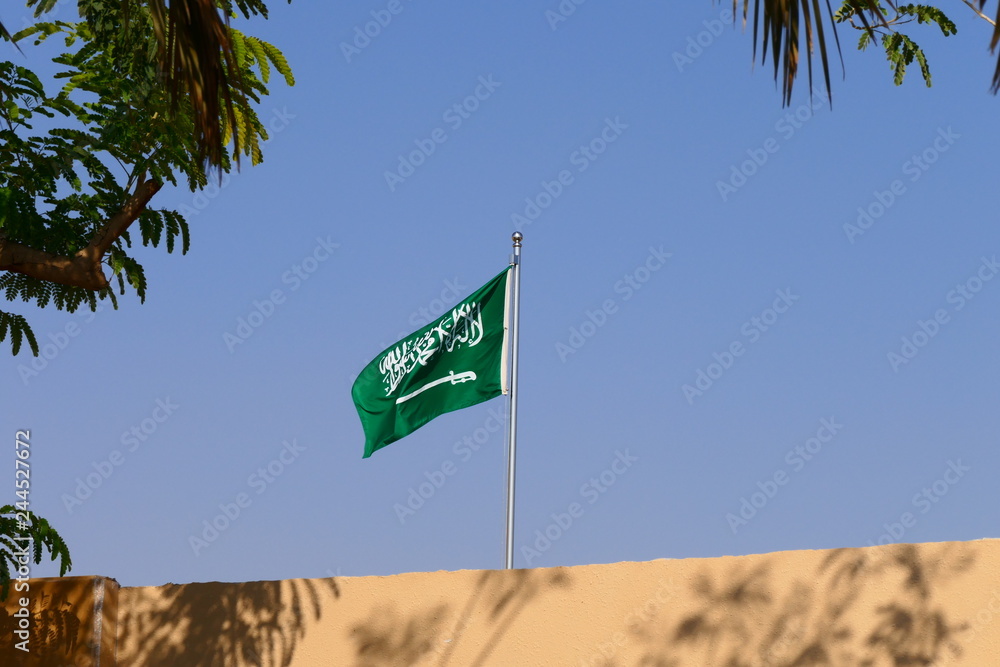 The flag of the Kingdom of Saudi Arabia waving in the historic Diriyah ...