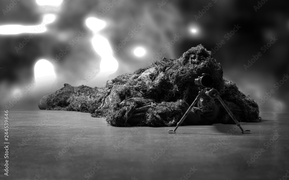 Foto de The sniper in disguise lies with a sniper rifle and aims at the ...