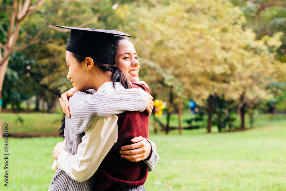 Smiling and happy Asian female graduate student hugging and embracing ...