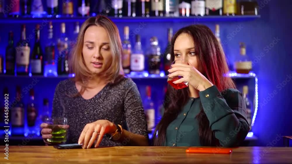 Two attractive young friends drinking cocktails together, toast to each ...