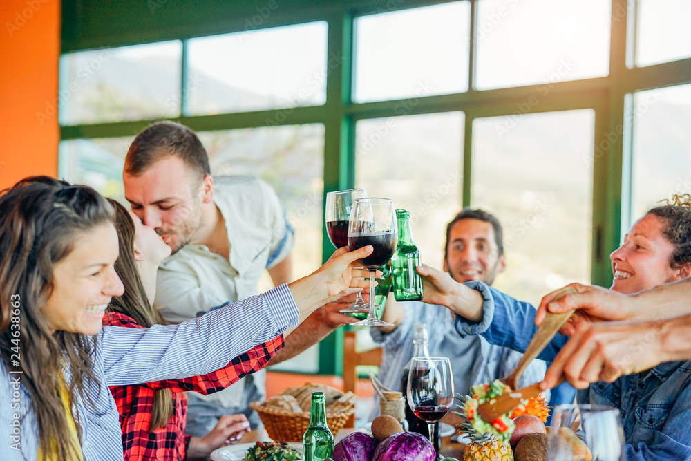 Happy friends cheering with glasses of red wine and beers at lunch ...