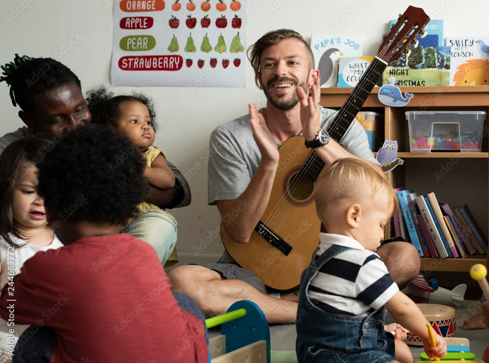Nursery children playing with musical instruments in the classroom ...