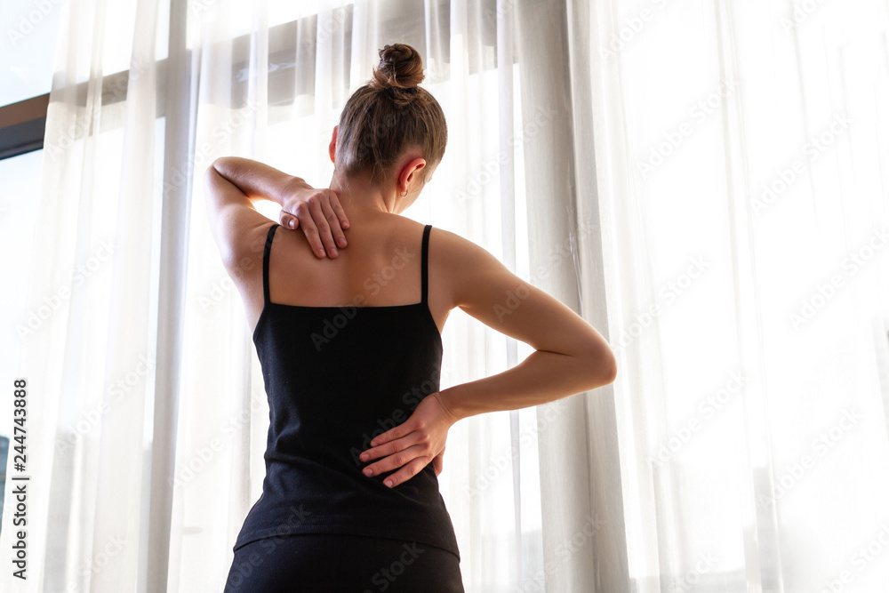 Young woman suffering from neck pain and backache, stretching the ...