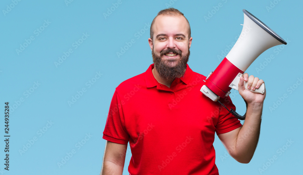 Young caucasian man yelling through megaphone over isolated background ...