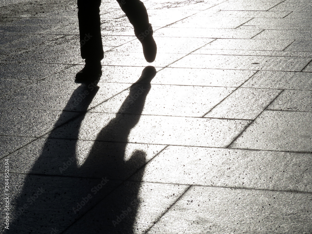 Black silhouette and shadow of man walking down the street. Hurrying ...