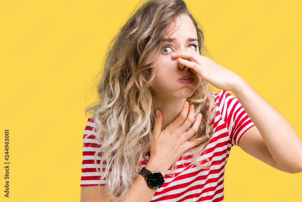 Beautiful young blonde woman over isolated background smelling ...