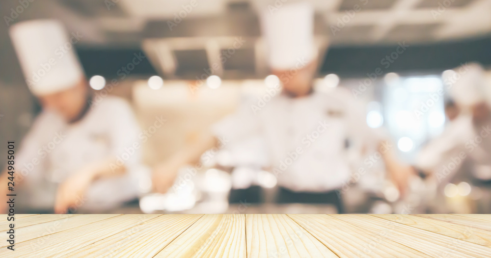 Empty Wood table top with Chef cooking in restaurant kitchen blurred ...