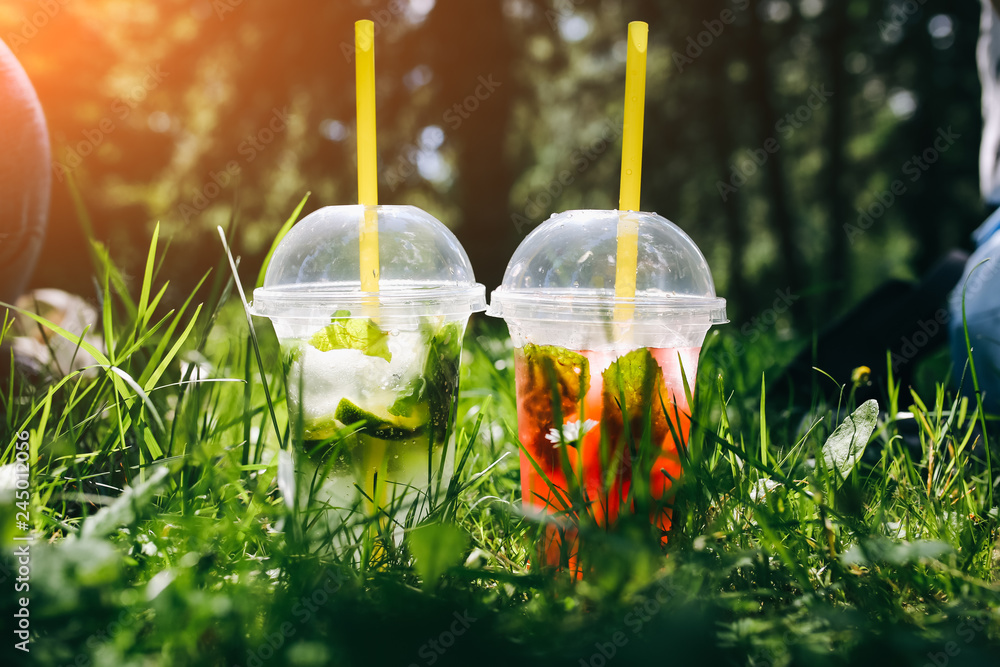 Two summer cocktails standing outdoors in the green grass. Cold non ...