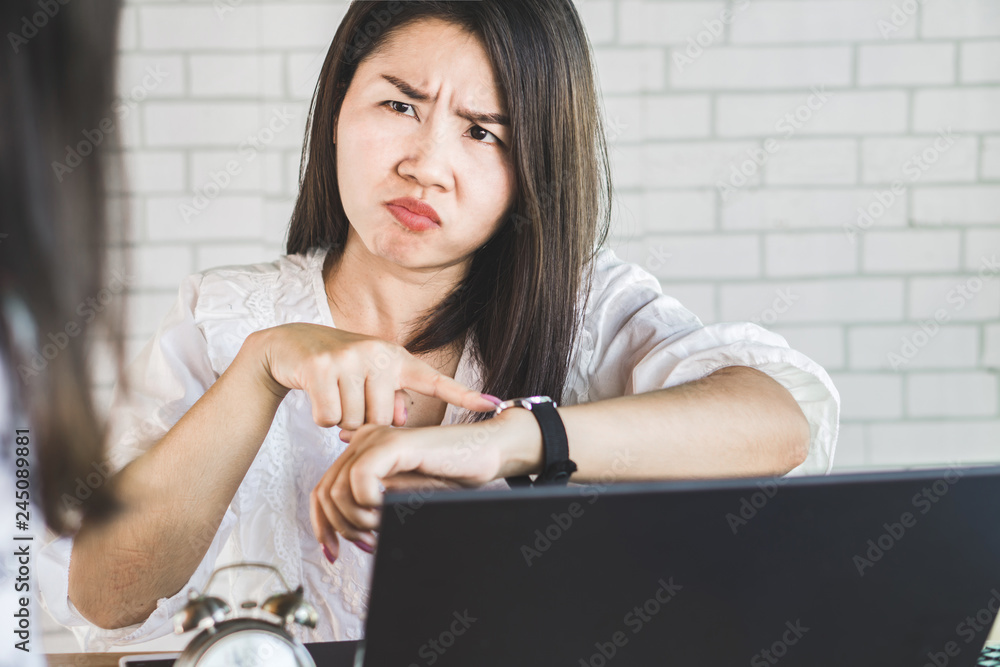 Angry Asian female manager pointing at her watch complaining her ...