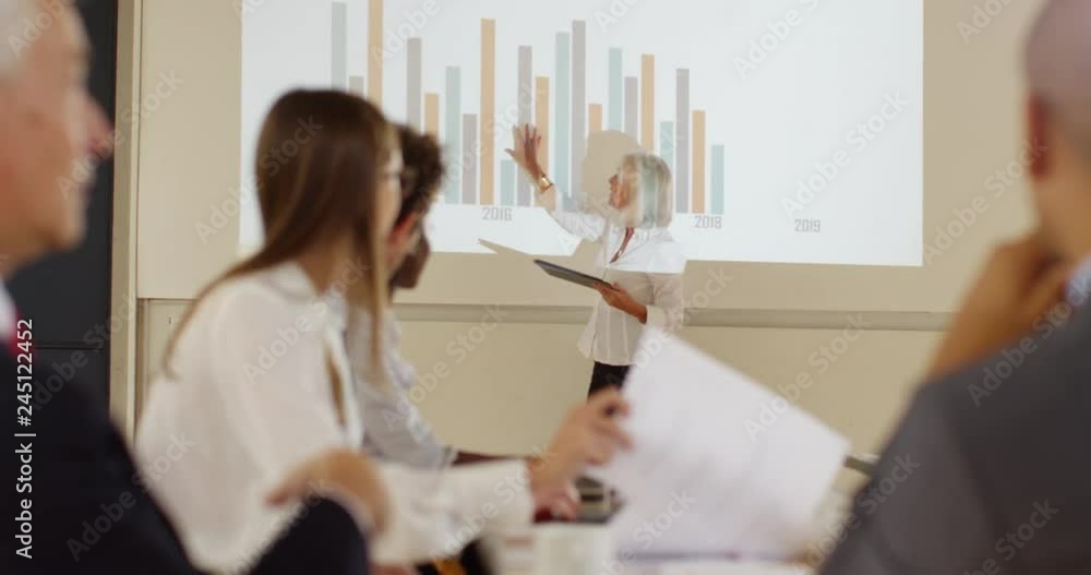 4K Cheerful businesswoman presenting sales graph to colleagues in a ...