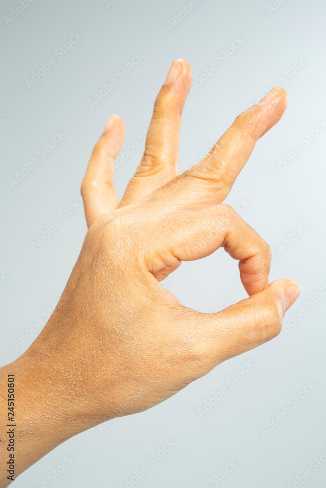 Woman's left hand symbol meaning " OK " on grey background, Close up ...