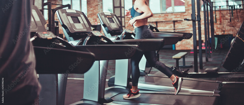 Healthy woman running on a treadmill in a gym. Sport and health concept ...