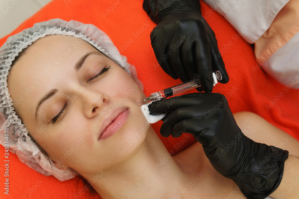 Beautician makes beauty injections in cheek on face of a woman ...