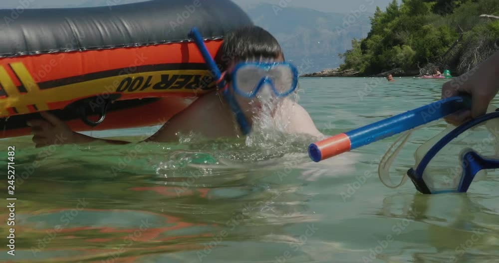 Vidéo Stock A young boy pops out from under an inflated raft in crystal ...