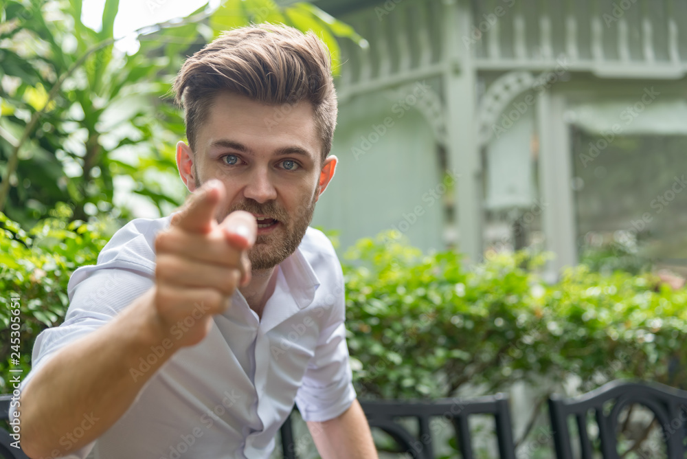 Young furious caucasian businessman shouting and pointing camera ...