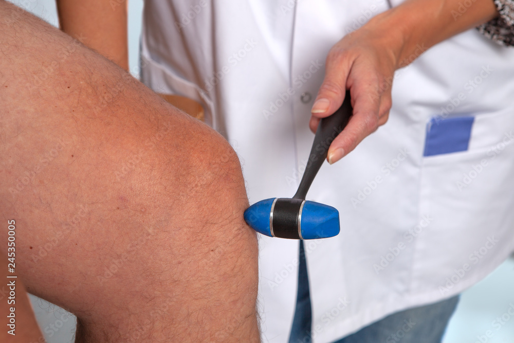 doctor examines the knee reflex of a patiënt with a reflex hammer Stock ...