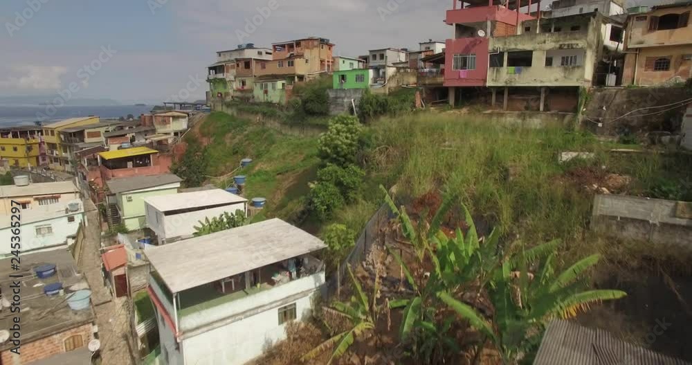 Favela Aerial: close-up angled flying up and over hilltop favela to ...
