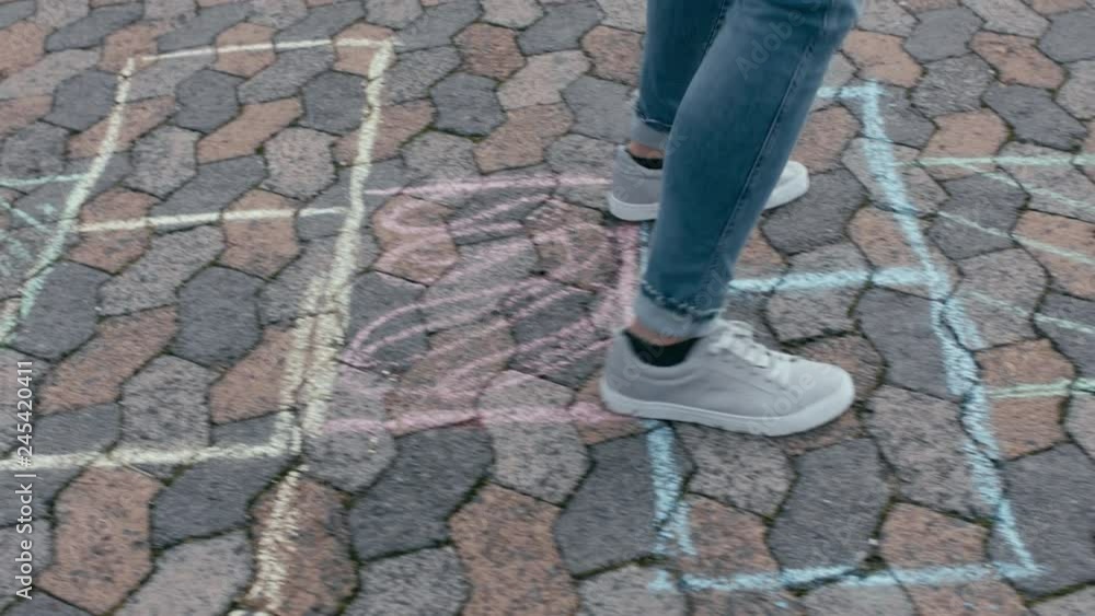close up teenage girl playing hopscotch game jumping on colorful ...